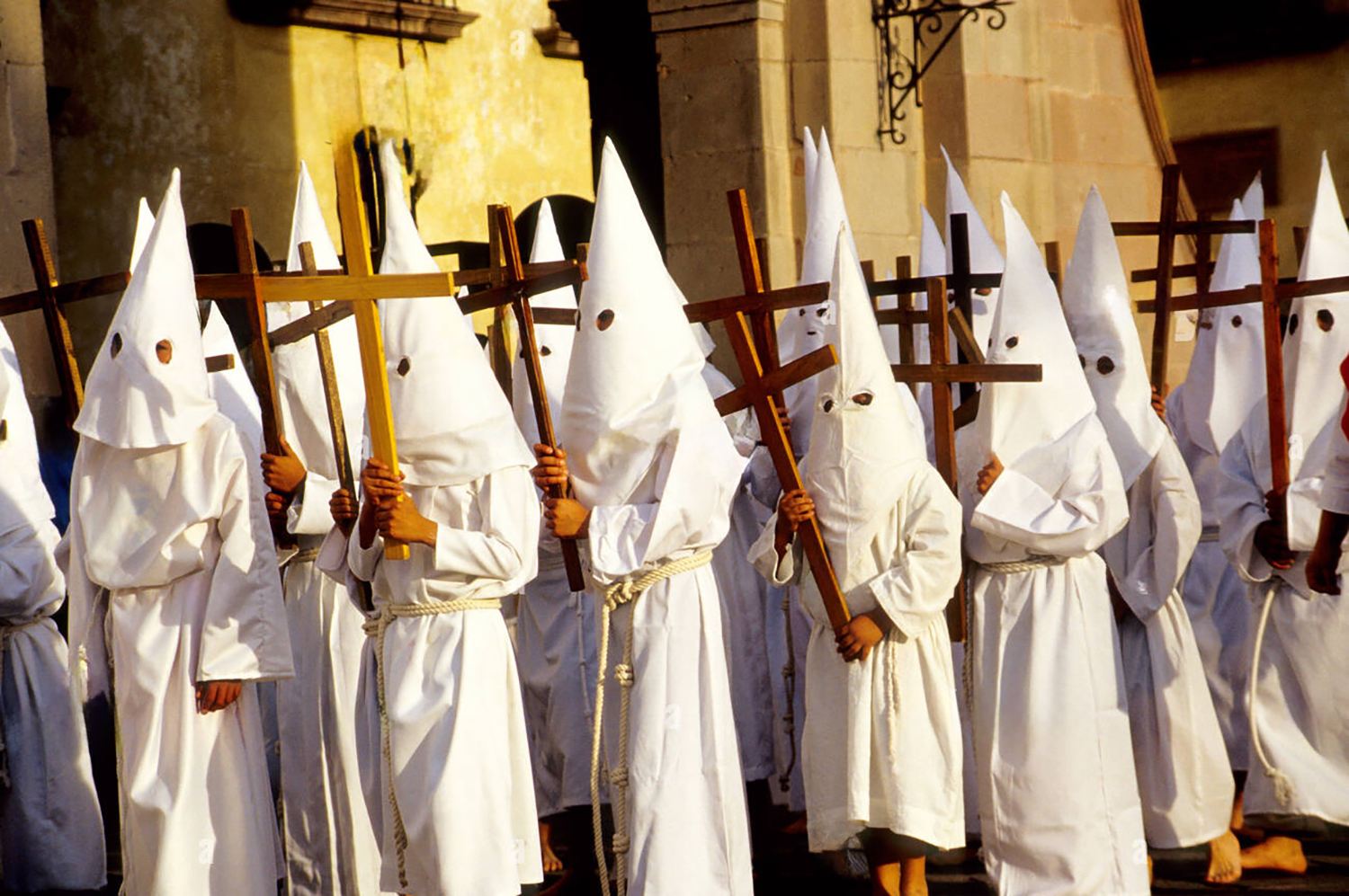 What is the meaning behind the pointed hoods (capriotes) worn in the ...